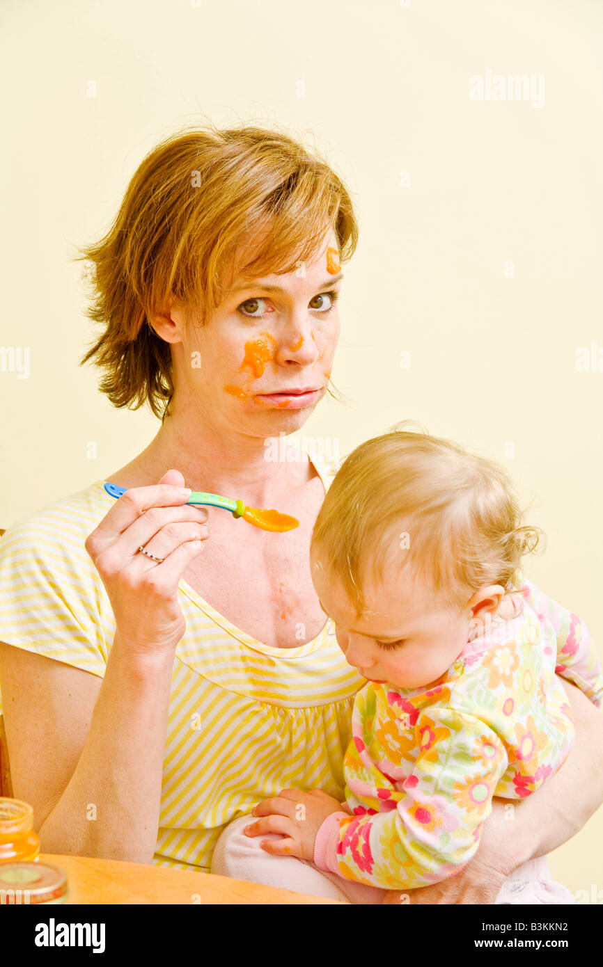 Frustrated mother trying to feed messy baby Stock Photo - Alamy