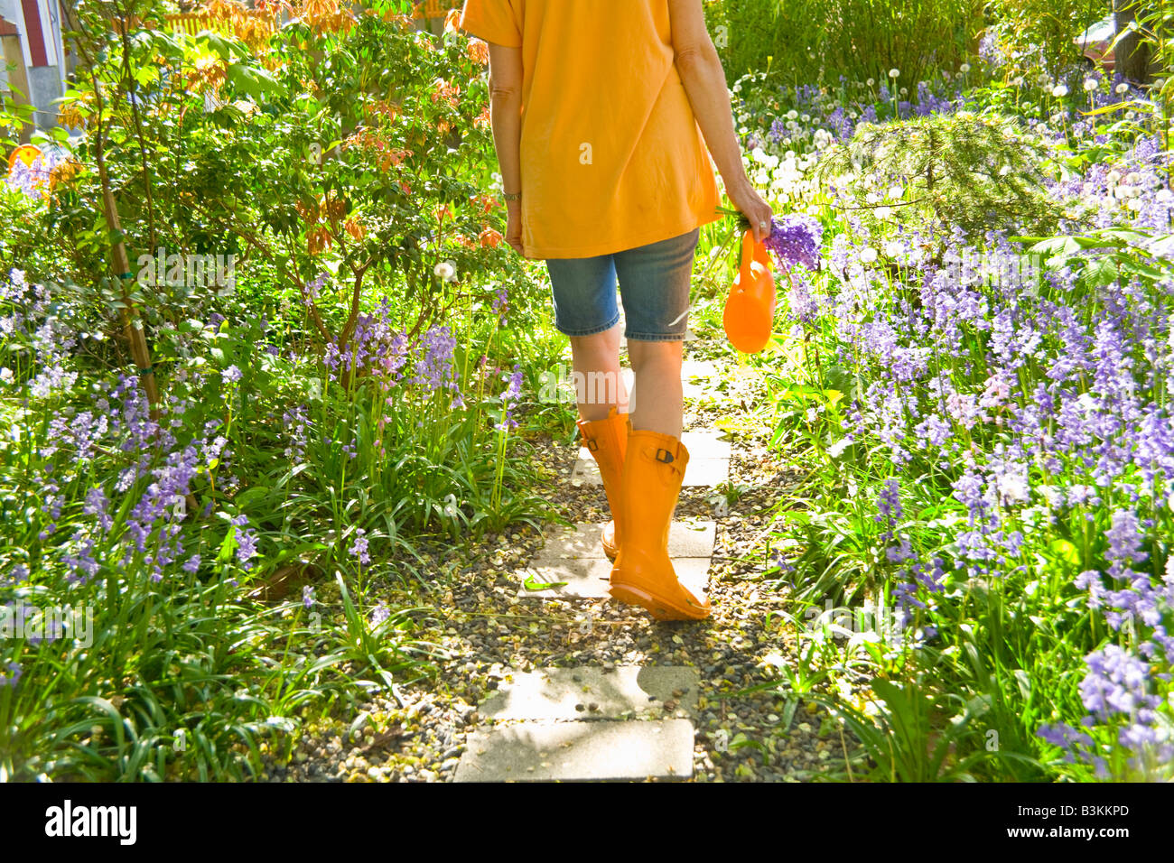 Woman walking through flowered path in garden Stock Photo - Alamy