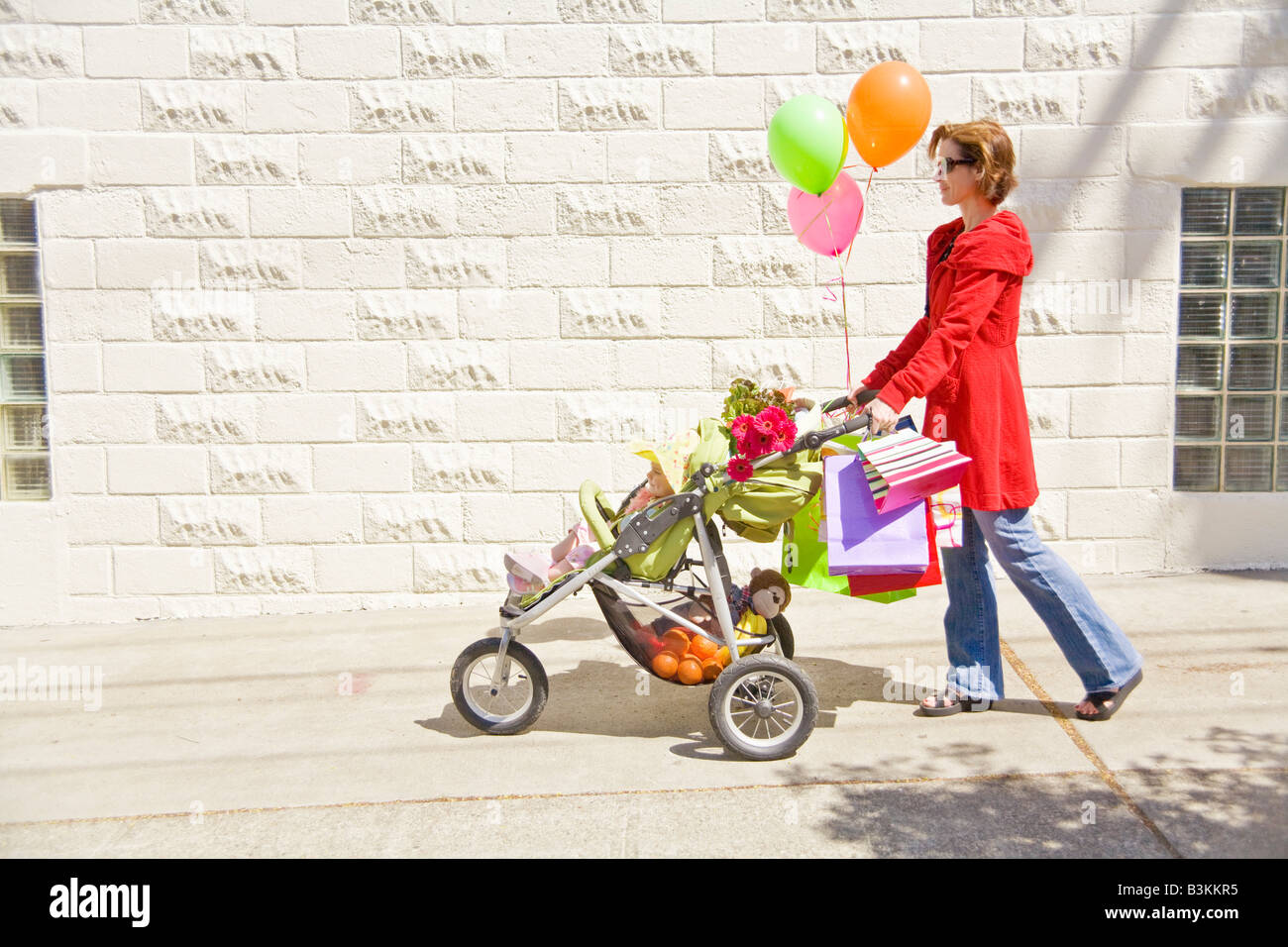 Woman pushing baby girl in stroller Stock Photo - Alamy