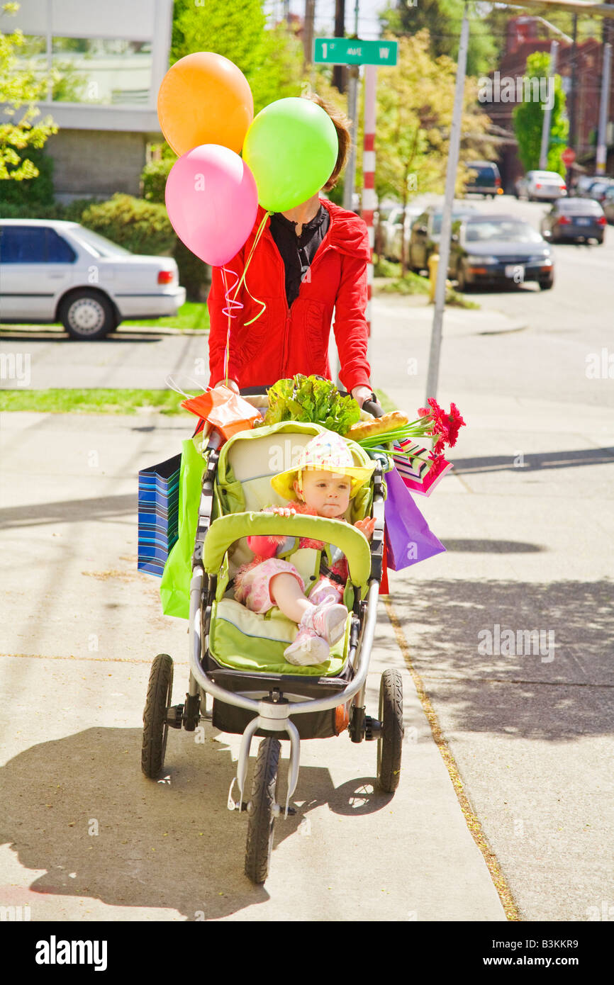Woman pushing baby girl in stroller Stock Photo - Alamy