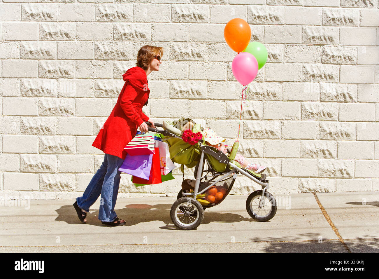 Woman pushing baby girl in stroller Stock Photo - Alamy
