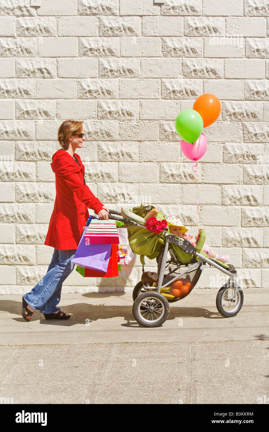 Woman pushing baby girl in stroller Stock Photo - Alamy