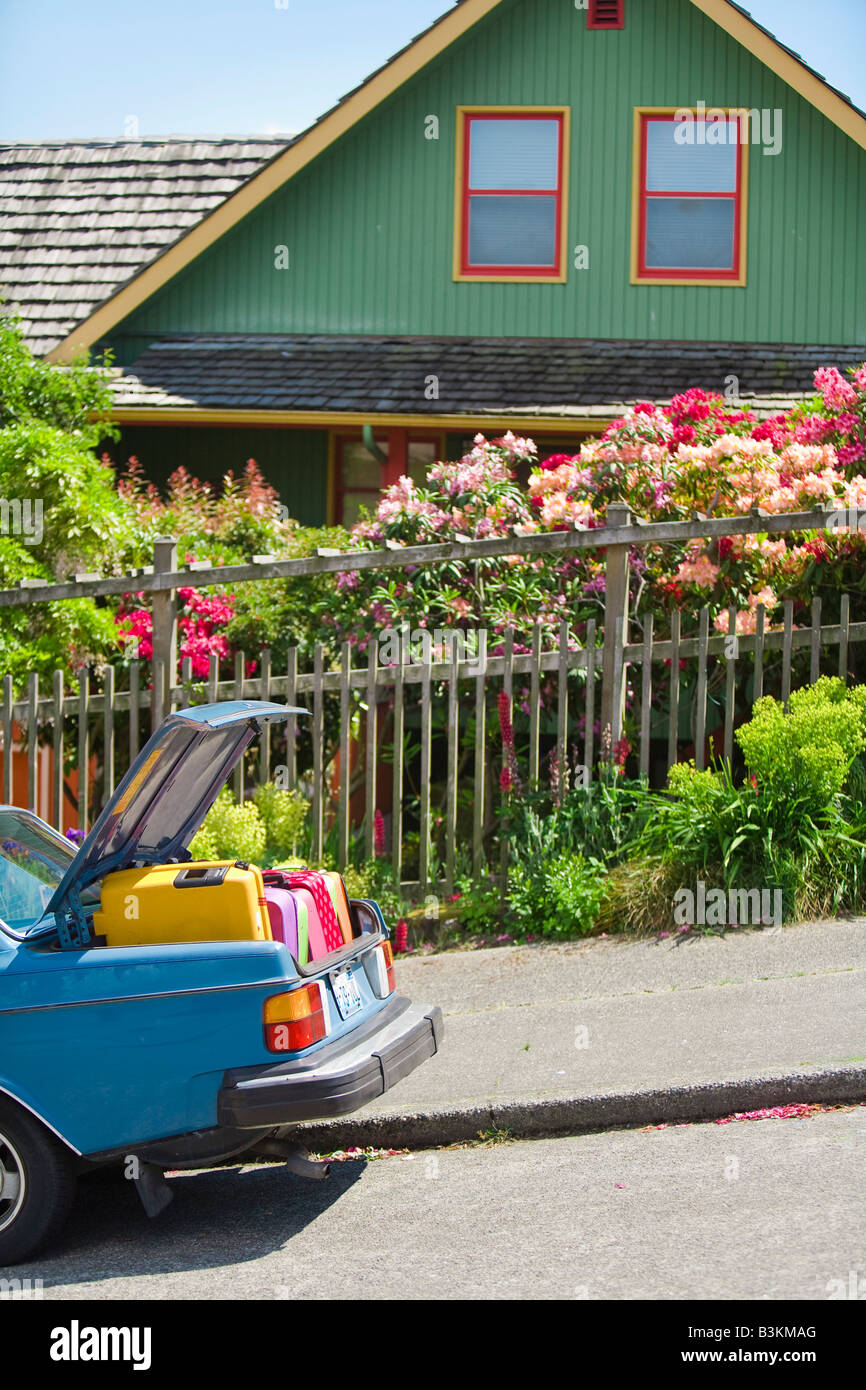 Car trunk loaded with colorful suitcases in front of house Stock Photo ...