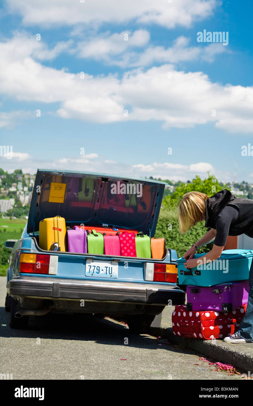 Woman loading car trunk with colorful suitcases Stock Photo - Alamy