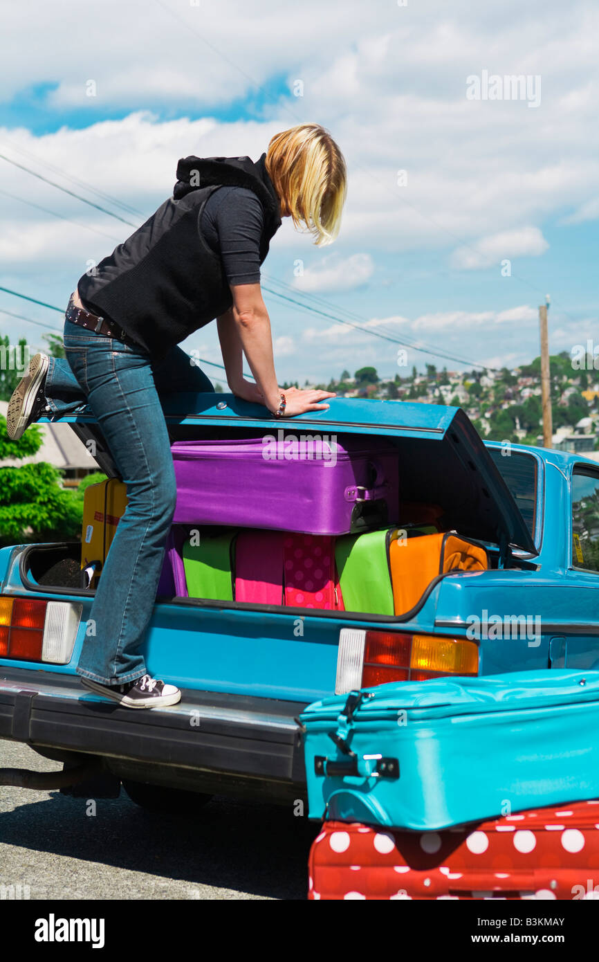 Woman loading car trunk with colorful suitcases Stock Photo - Alamy