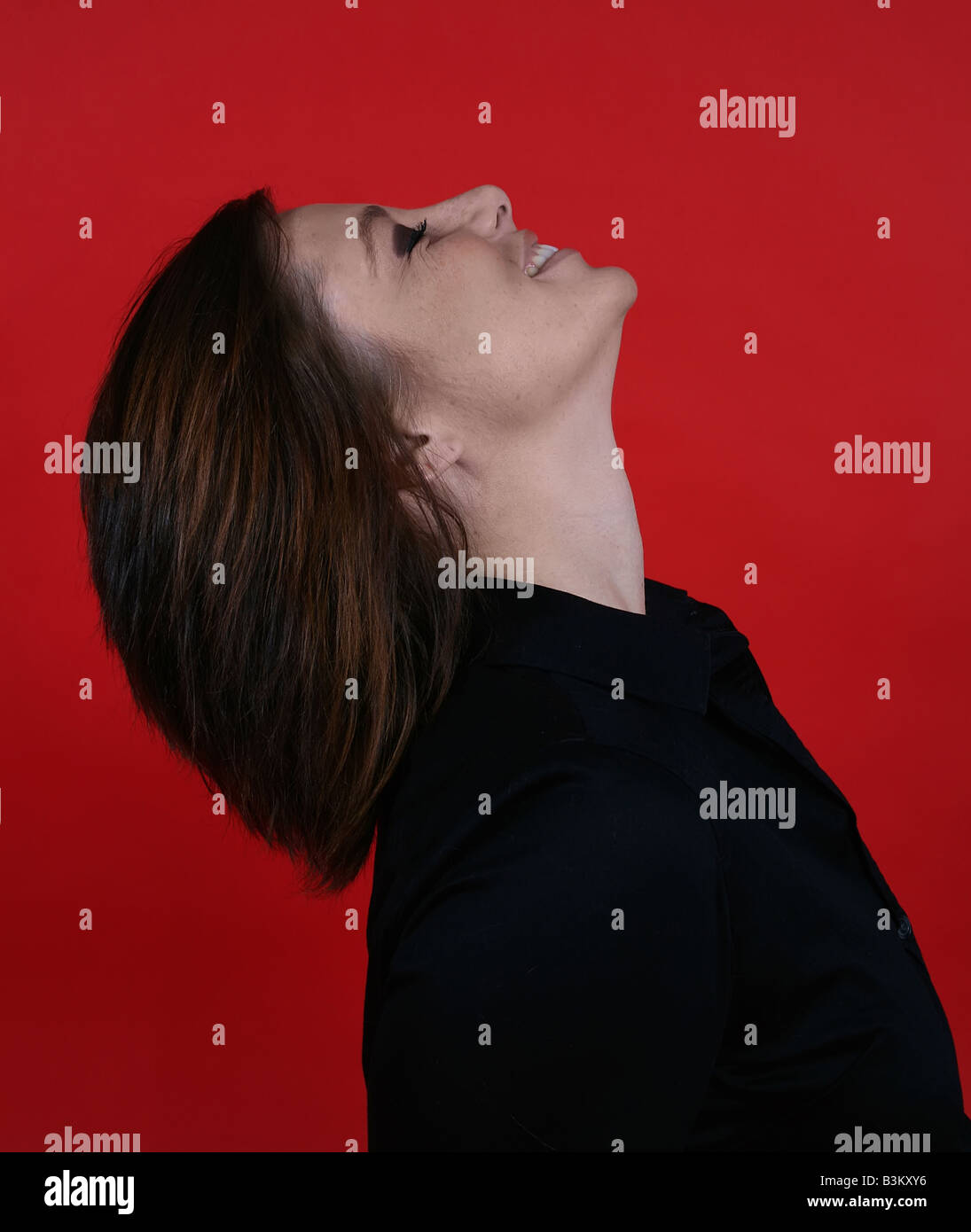 a girl laughing in the side profile on a red background Stock Photo - Alamy