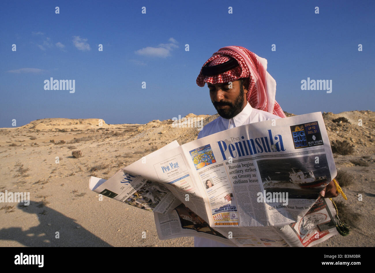 Qatar, Middle East, Asia, Arab Man reading a newspaper in the desert ...