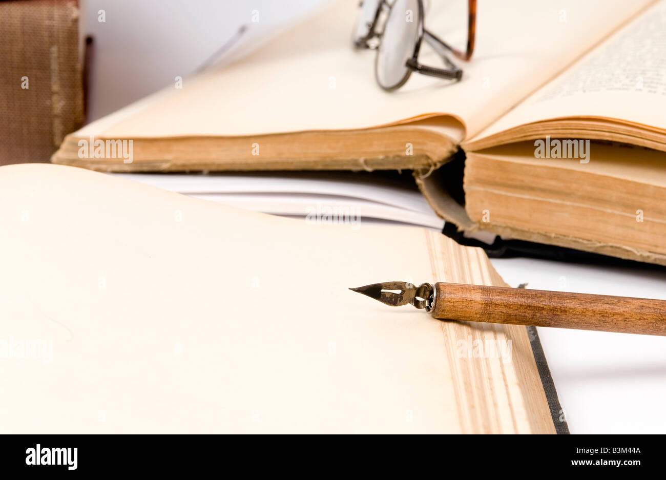 An old book that is open with a calligraphy pen on top Stock Photo - Alamy
