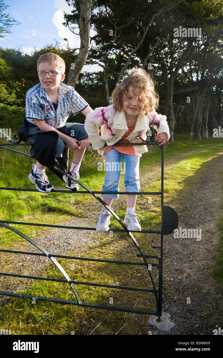 Two Scottish children a boy and a girl play on a gate on the Isle of ...