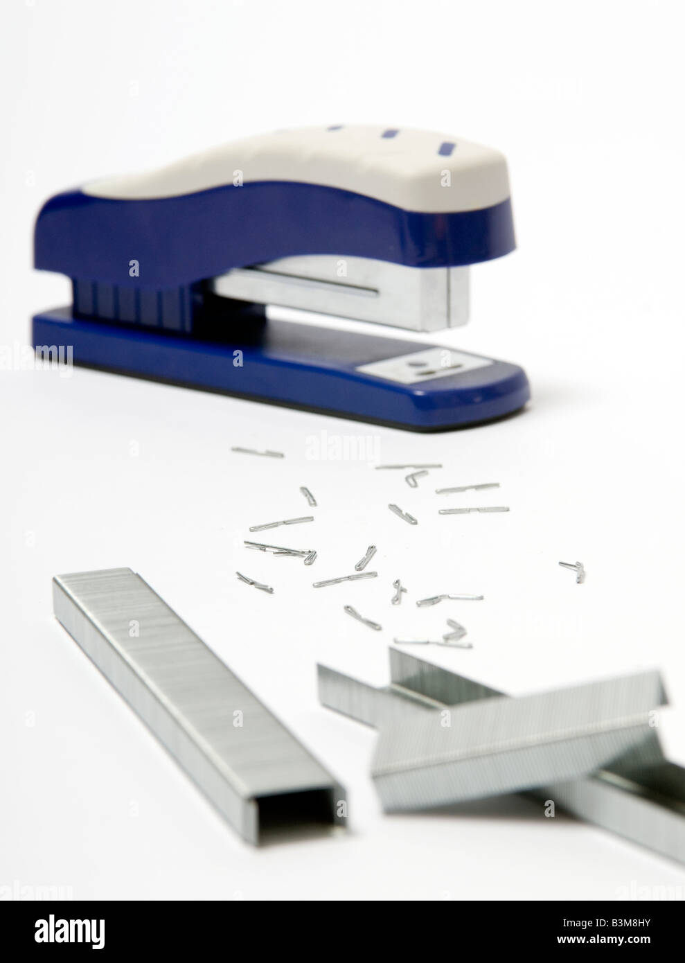 An office stapler with used staples and a small pile of new ones in ...