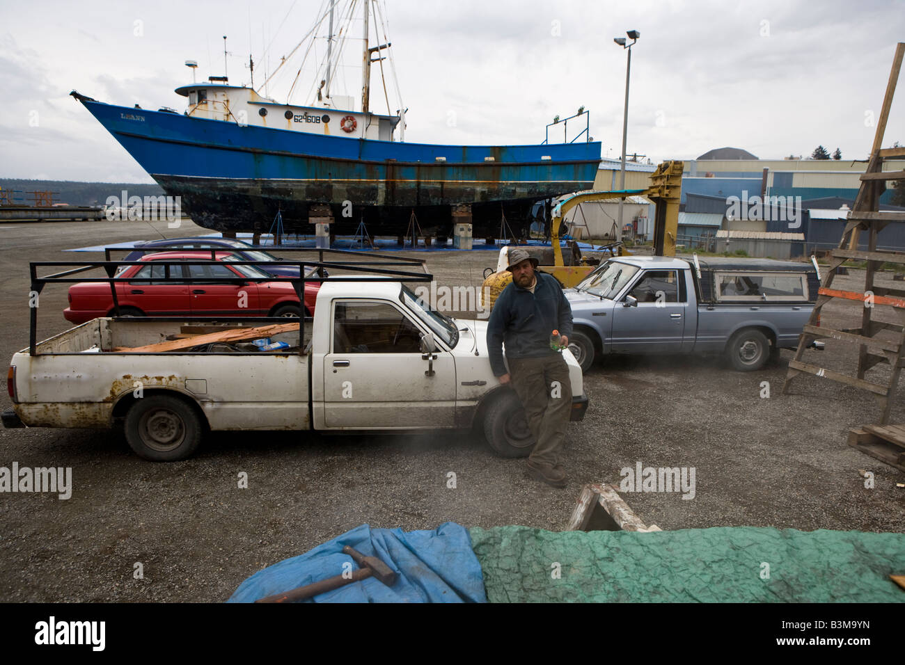 A shipwright takes a moment to relax while working on the sailboat ...