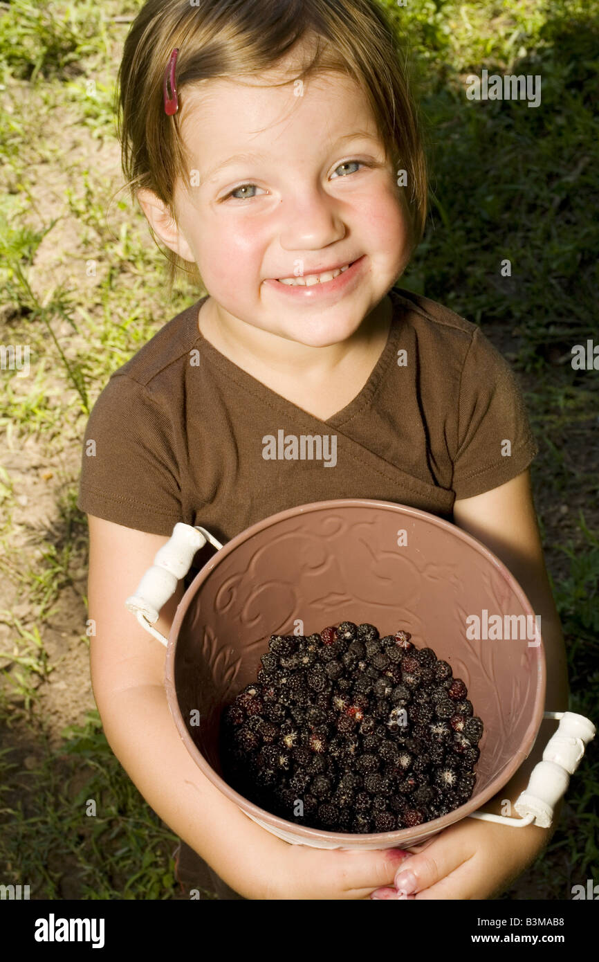 A young girl collecting wild berries in a bucket Stock Photo - Alamy