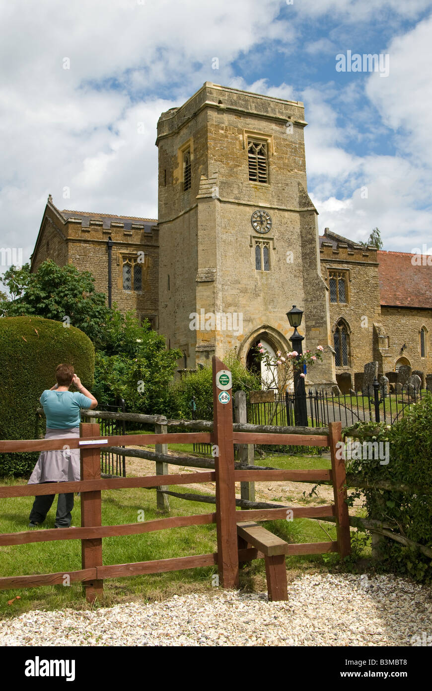 A lady taking a photograph of St Thomas a Becket church at Sutton under ...