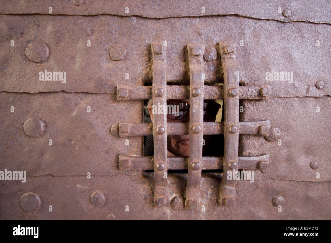 Person looking through barred window of ancient town door Stock Photo ...
