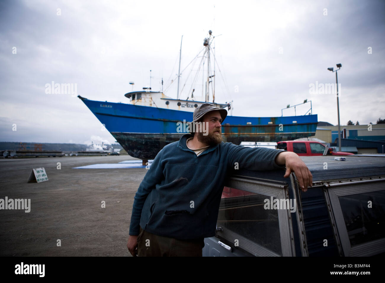 A shipwright takes a moment to relax while working on the sailboat ...
