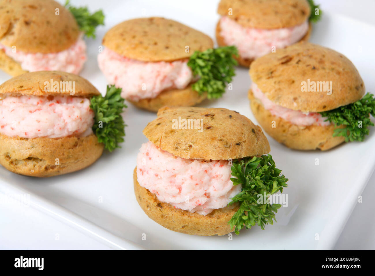 A pureed prawn meat filling in small brown bread canapes on a plate ...