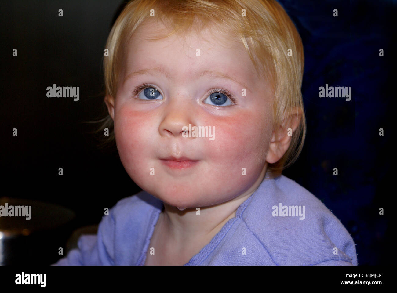 Close-up of small blond child looking up with pixie mouth and drop of ...