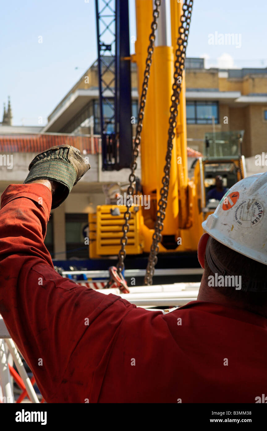 Construction worker directing crane on site Stock Photo - Alamy