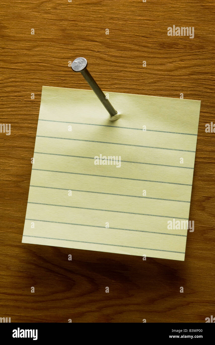 Lined yellow sticky note nailed to wood background Stock Photo - Alamy