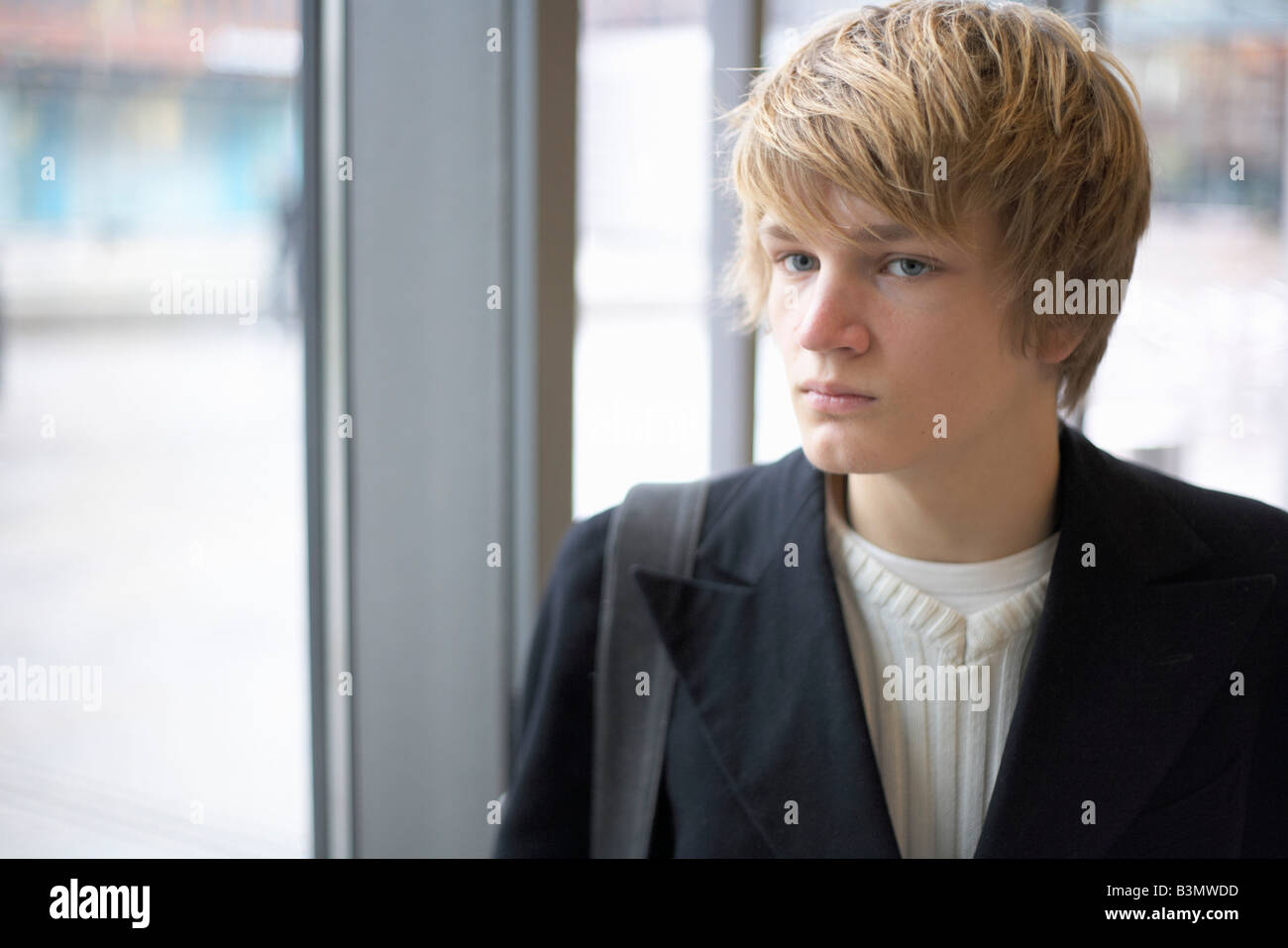 Teenage boy near window in urban building, interior Stock Photo - Alamy