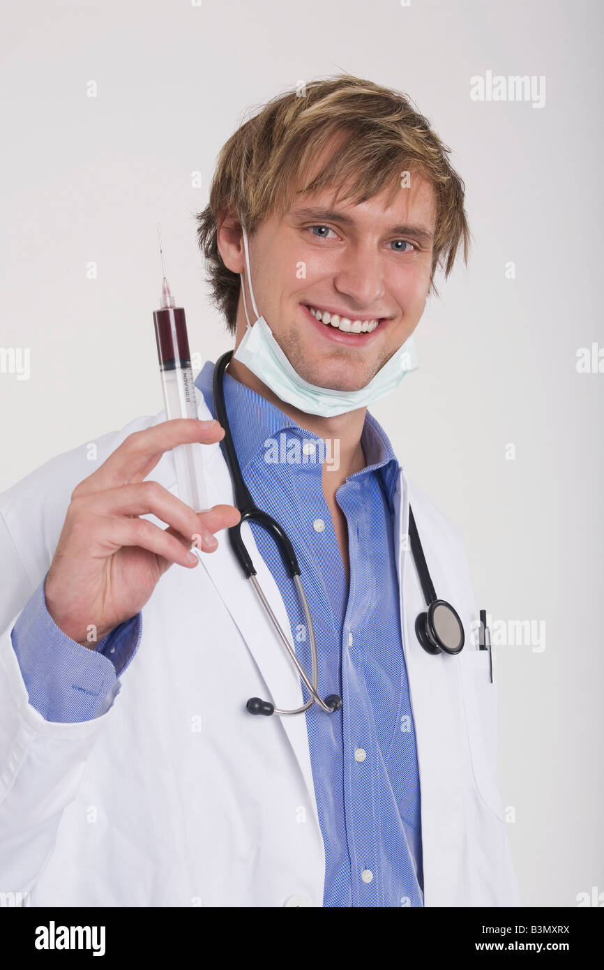 Young doctor holding a syringe, smiling Stock Photo - Alamy