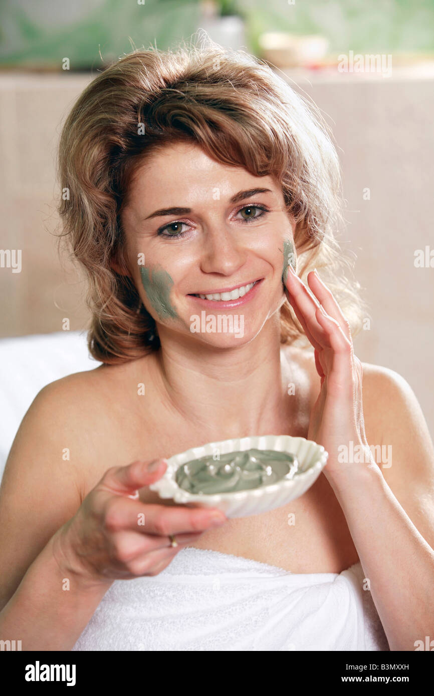 Young woman applying facial mask, smiling, portrait Stock Photo - Alamy