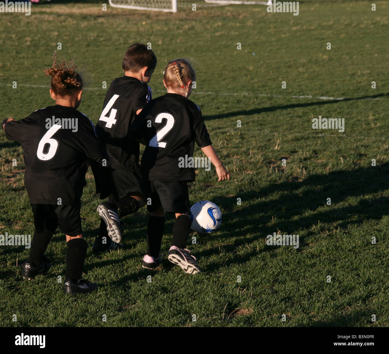 Three young children playing soccer game Stock Photo - Alamy
