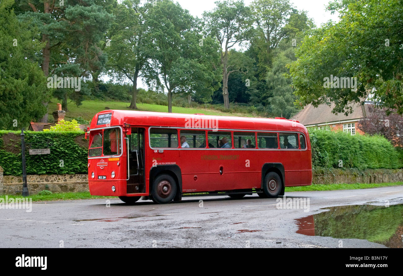 Old fashioned red English bus, driving through the countryside in ...
