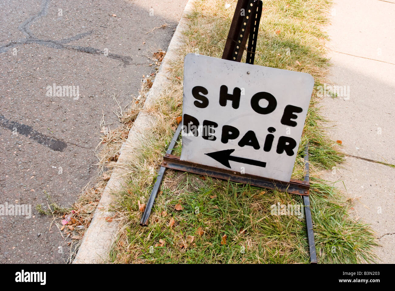 Shoe repair sign laying on a city sidewalk Stock Photo - Alamy