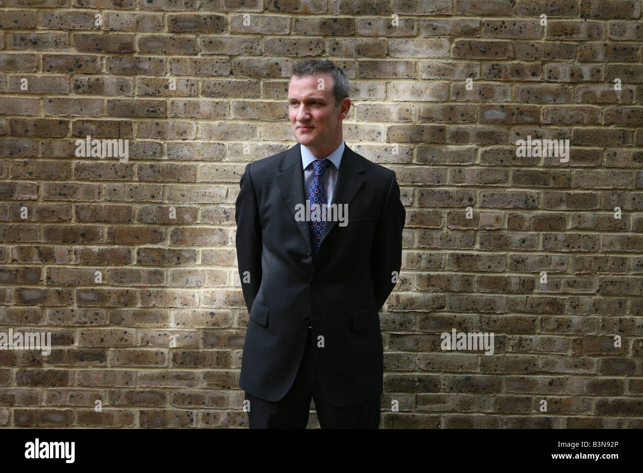 a portrait of a solicitor standing outside his office next to a brick ...
