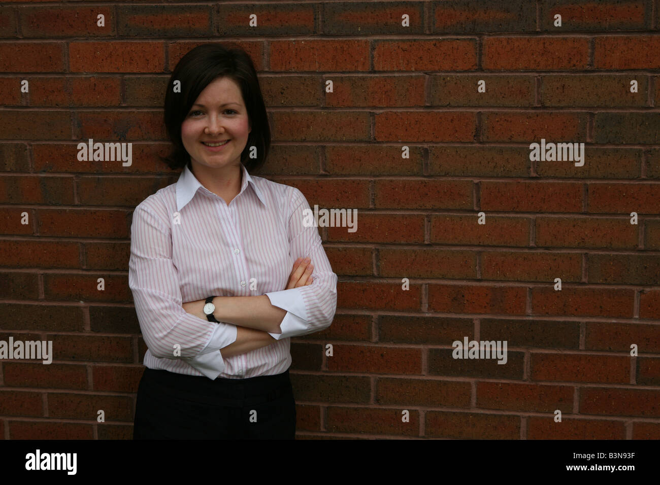 a portrait of a beautiful female solicitor leaning on a fence and ...