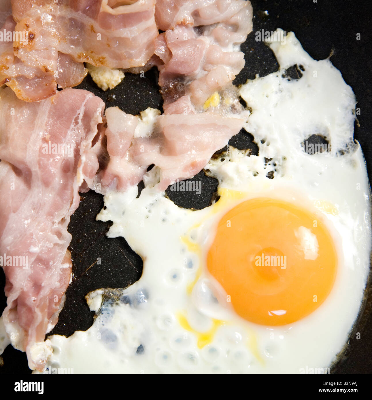 egg and bacon frying in a pan Stock Photo - Alamy