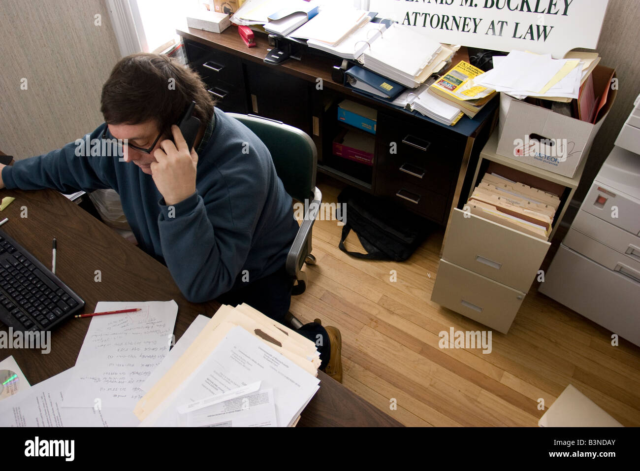 white male sitting at messy desk and computer with papers around him ...