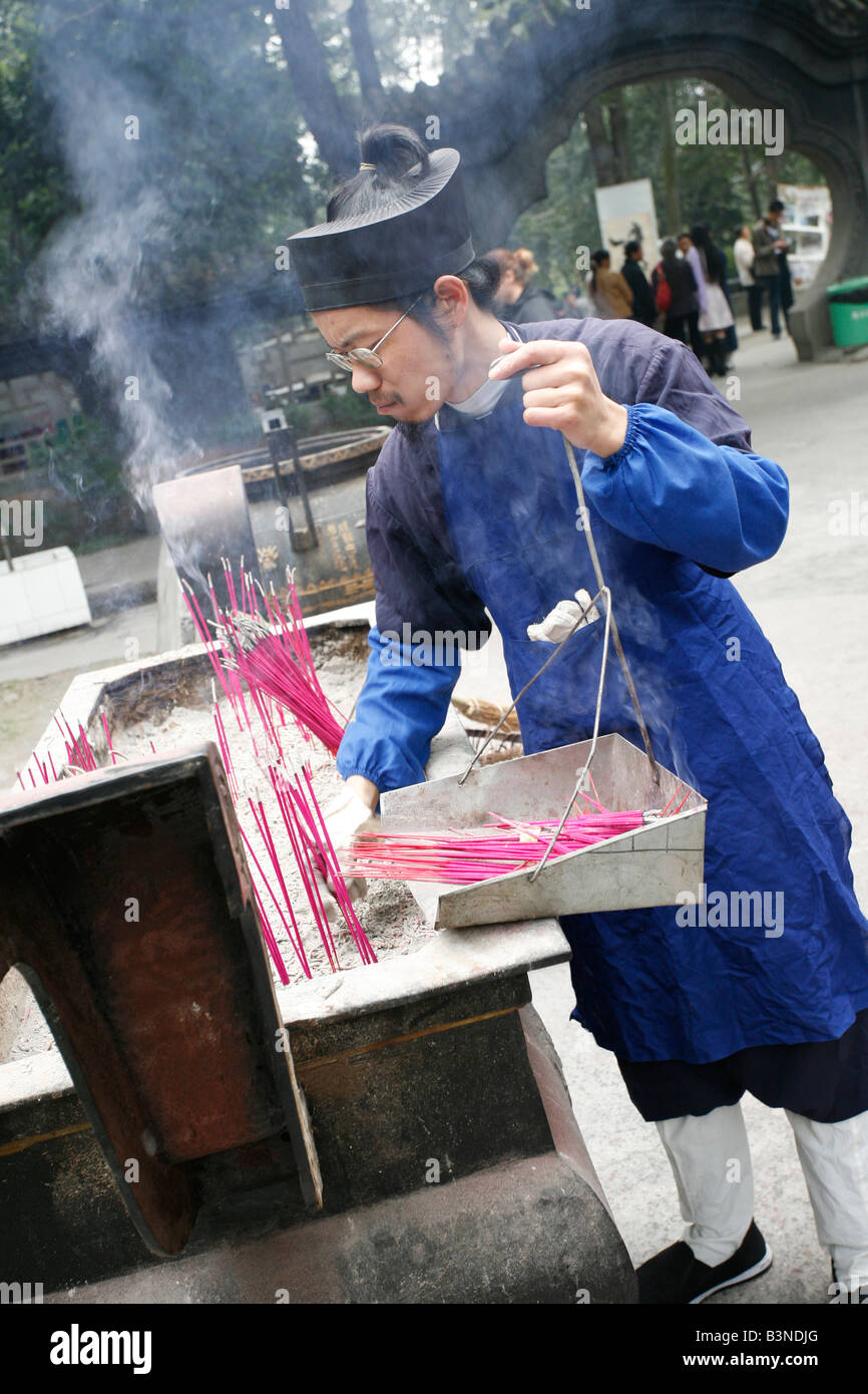 Temple worker gathering incense from urn at Wu Hou Memorial Temple ...