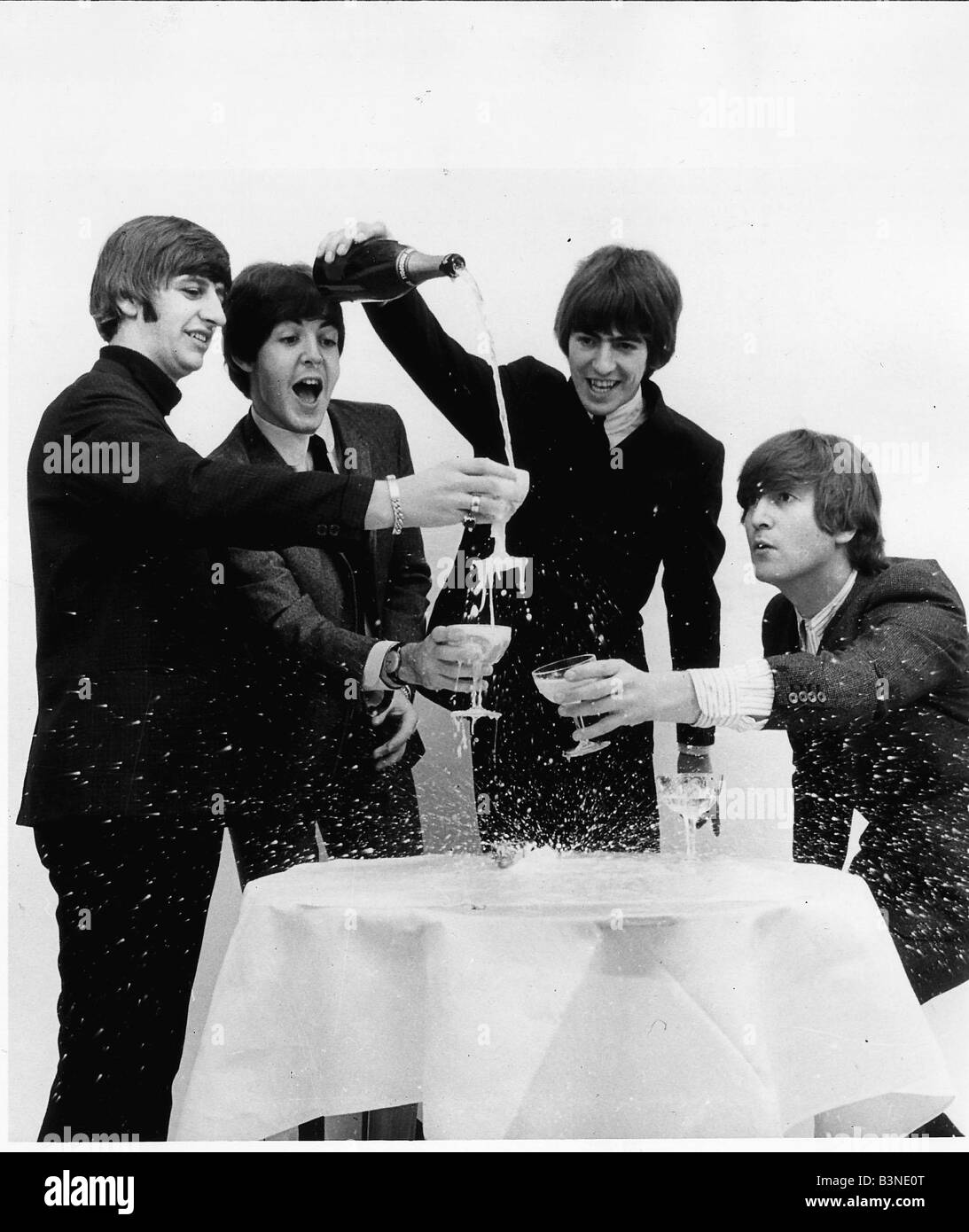 Beatles sitting round a table with glasses of champagne Stock Photo - Alamy