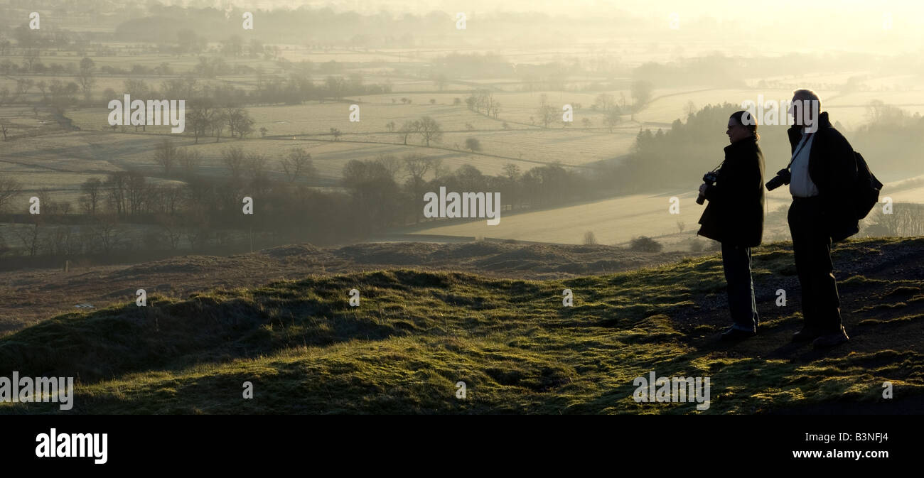 two walkers looking out over the valley through the mist towards ...
