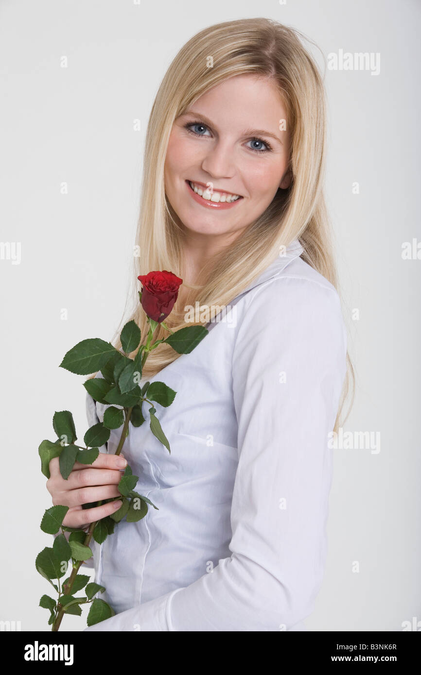 Young woman holding a rose, smiling, portrait Stock Photo - Alamy