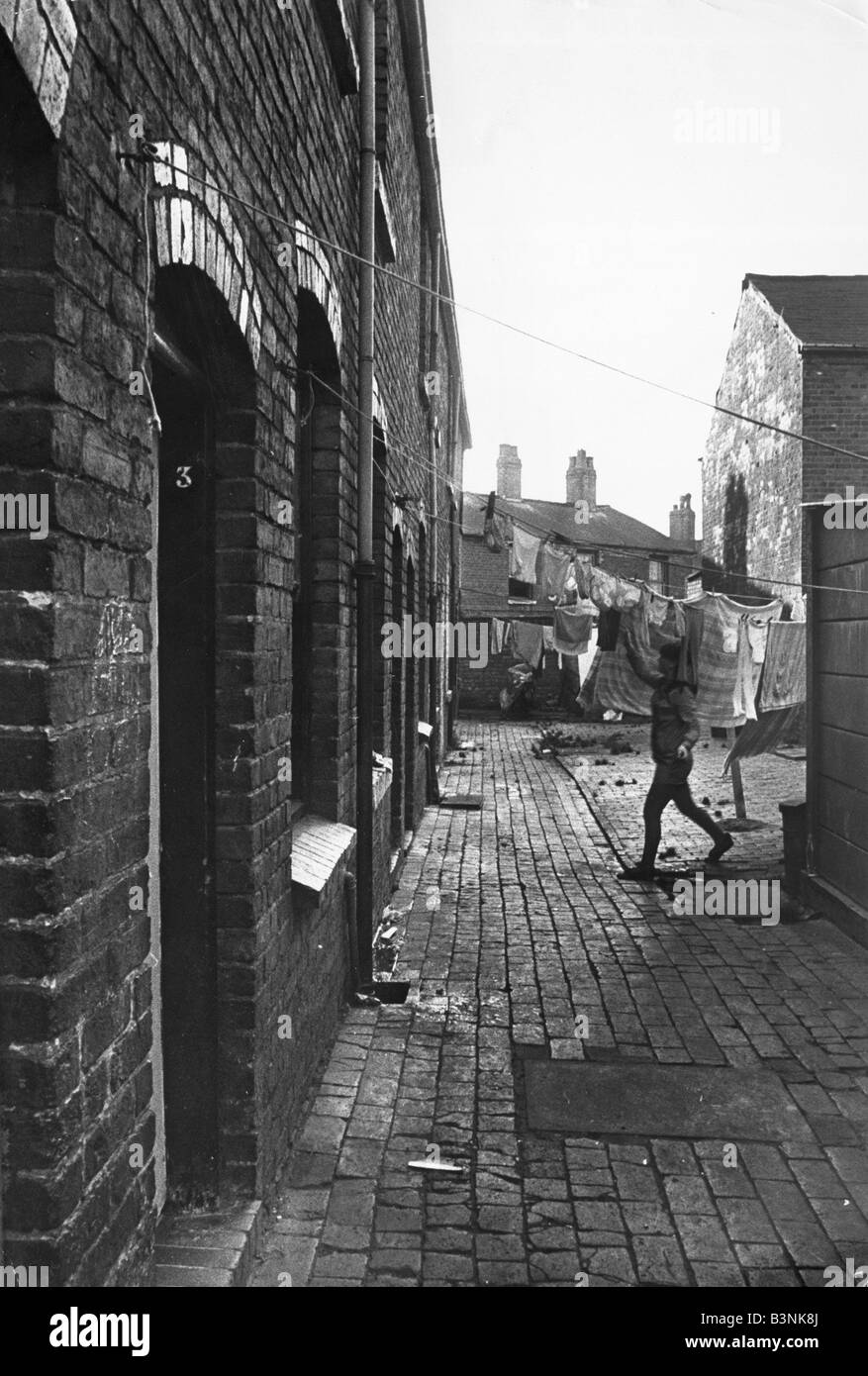 Exterior view of a Birmingham terraced house showing a woman hanging ...