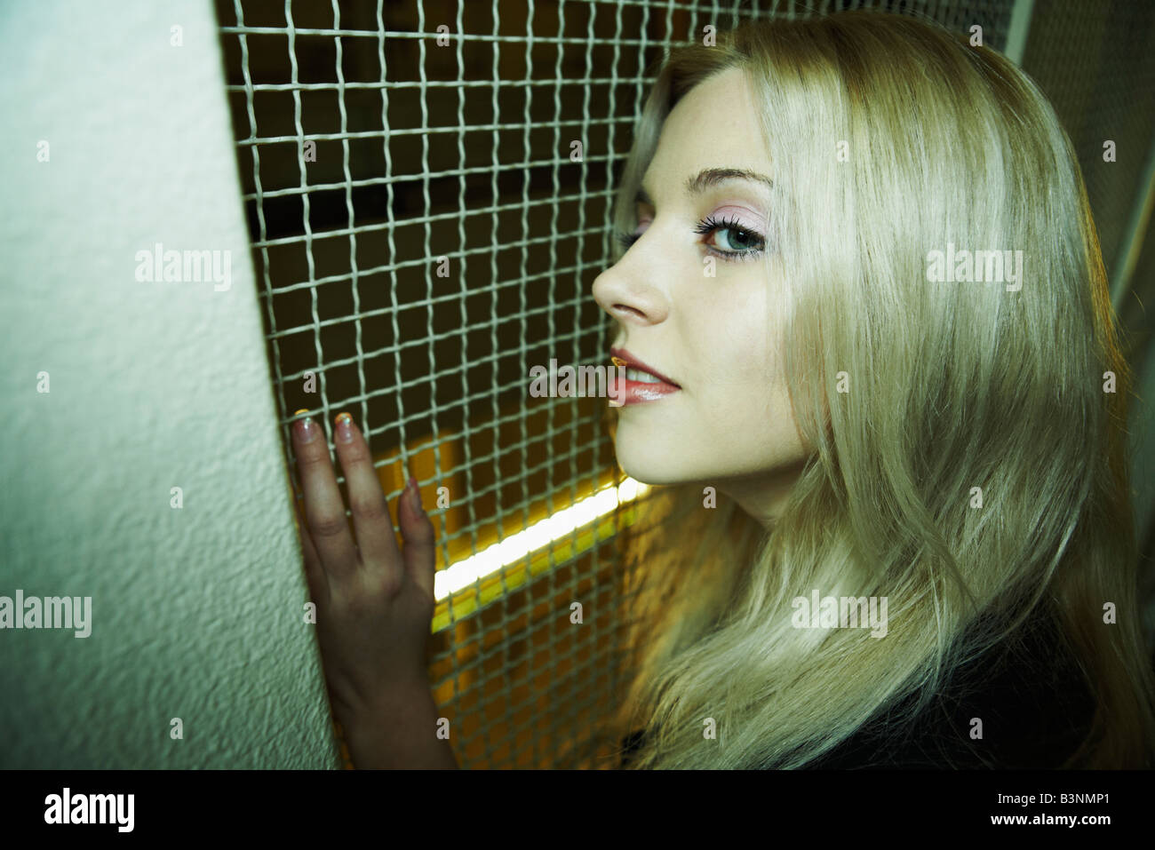 Young woman leaning to elevator net, looking away Stock Photo - Alamy