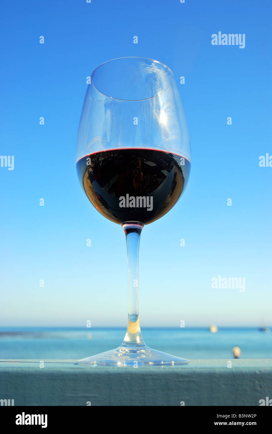 Glass of red wine on a restaurant s deck railing by the ocean beach ...