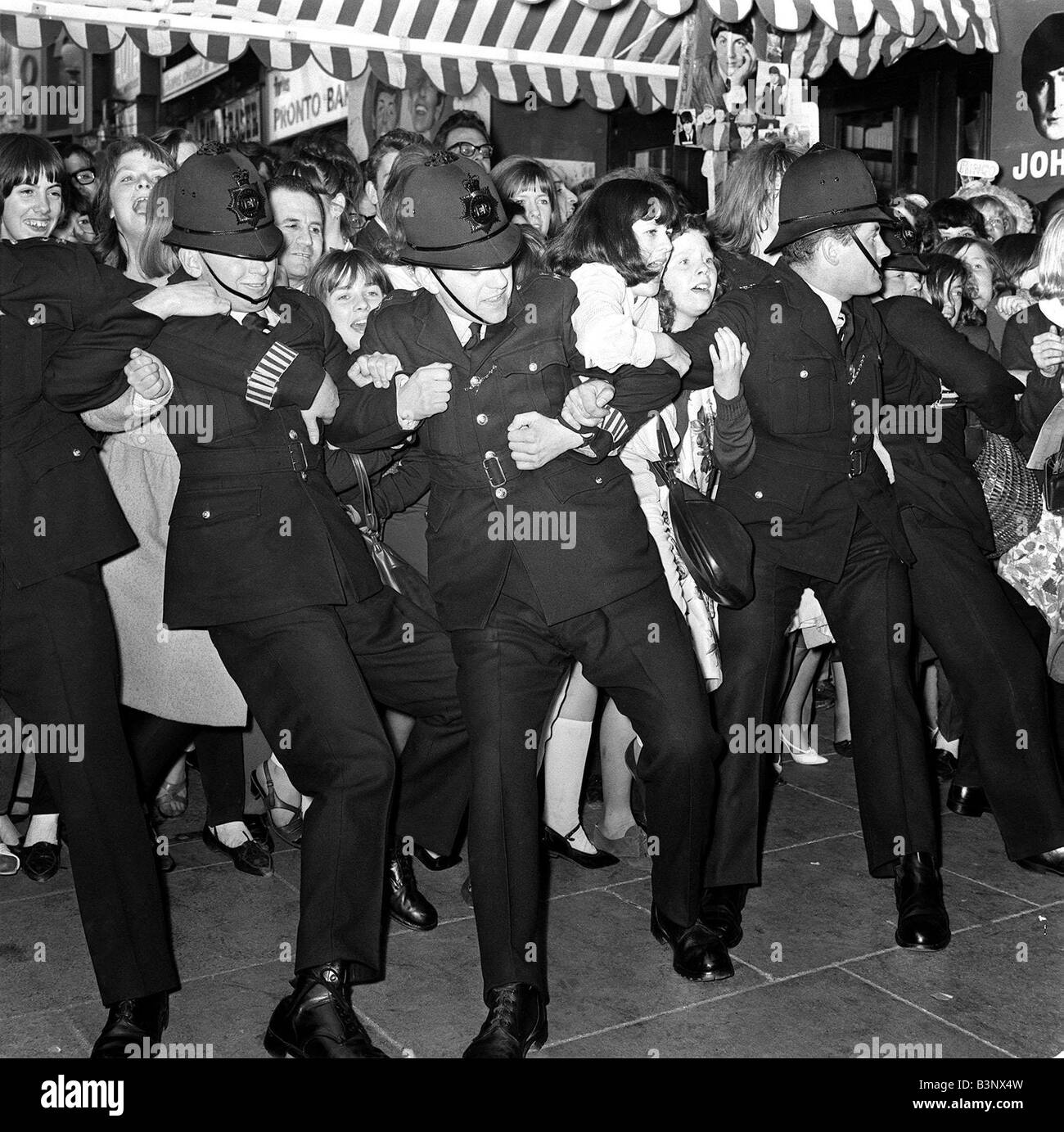 The Beatles July 1964 Police holding back crowds of fans who are ...