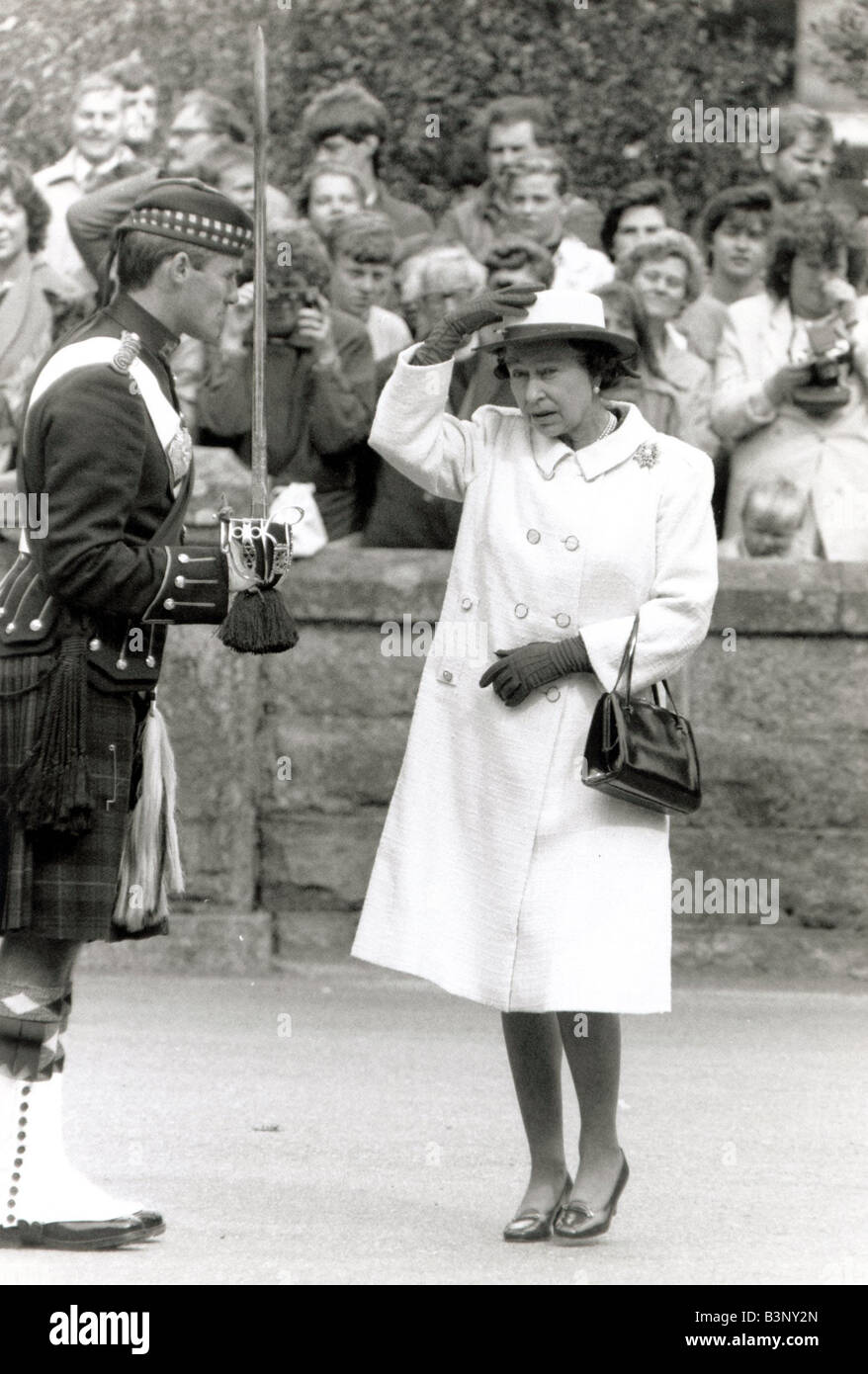 Queen Elizabeth II looking scared and gormless Holding hat on head ...