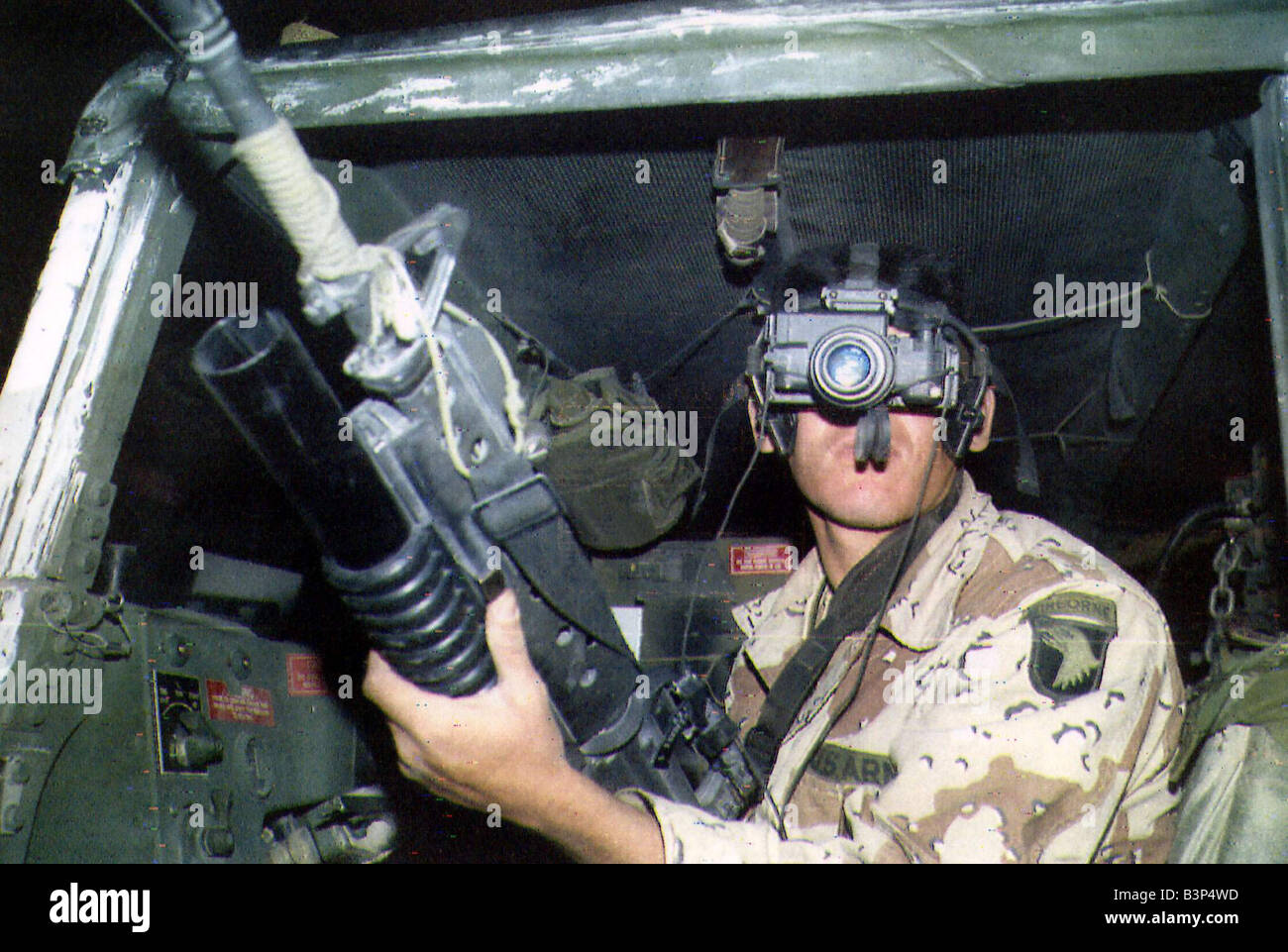 An American soldier looking through a night vision scope and holding a ...