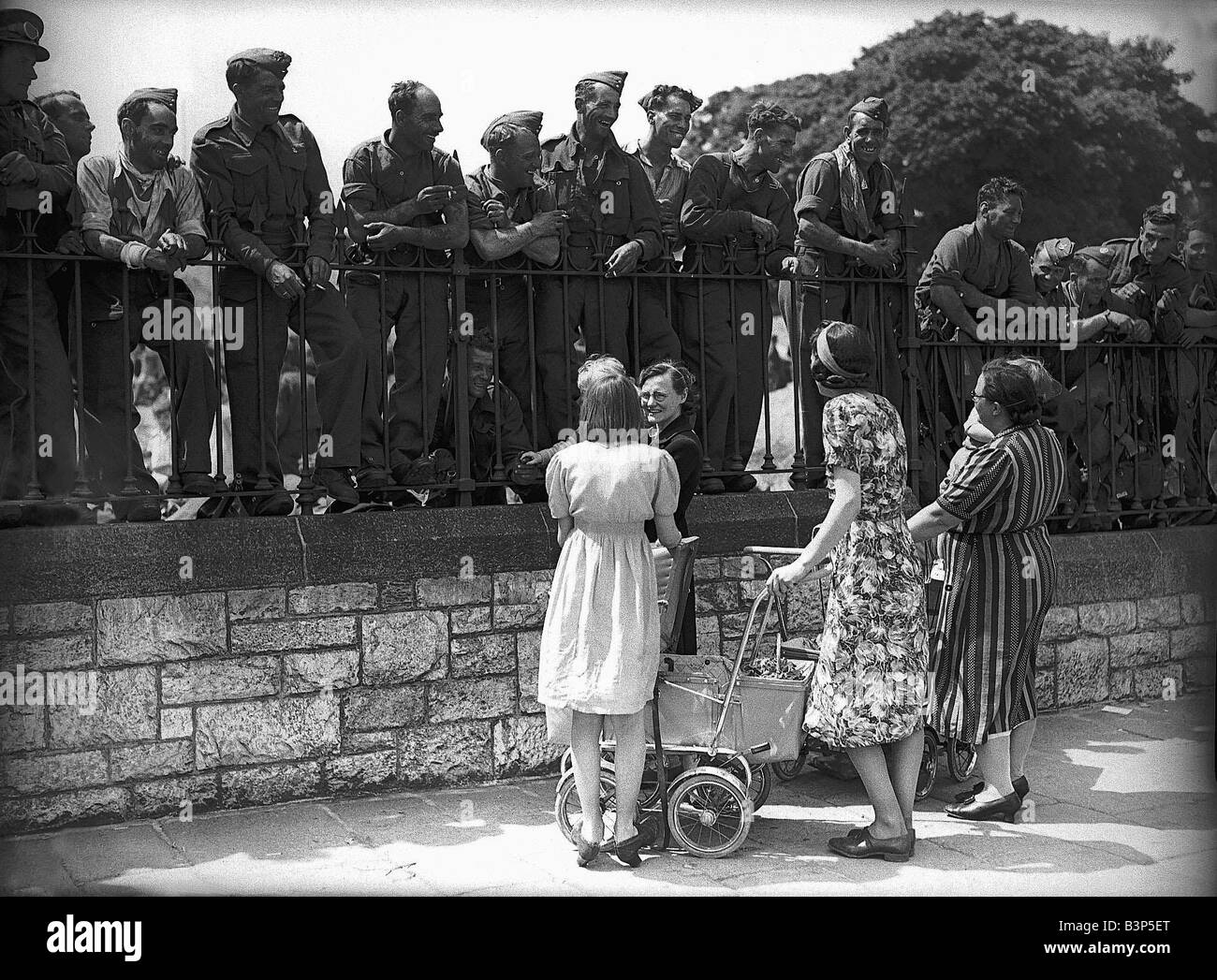 Soldiers talking to women with children during WW2 Stock Photo - Alamy