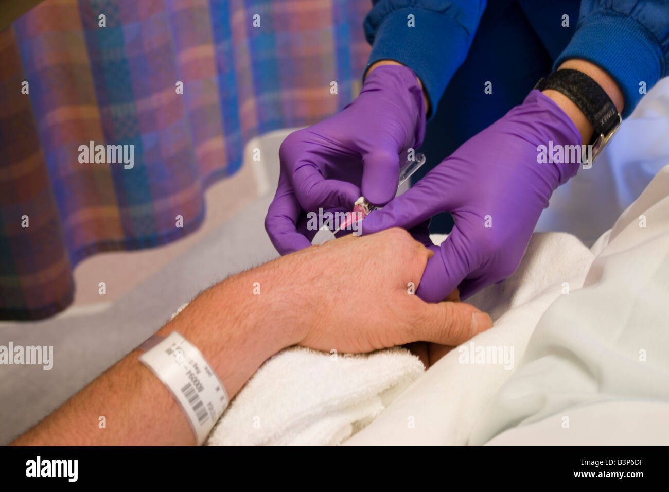 Nurse inserting an IV tube into a male patient's hand Stock Photo - Alamy