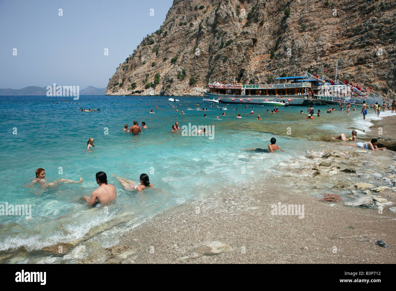 Tourists bathing in turquoise sea water on Butterfly Valley beach ...