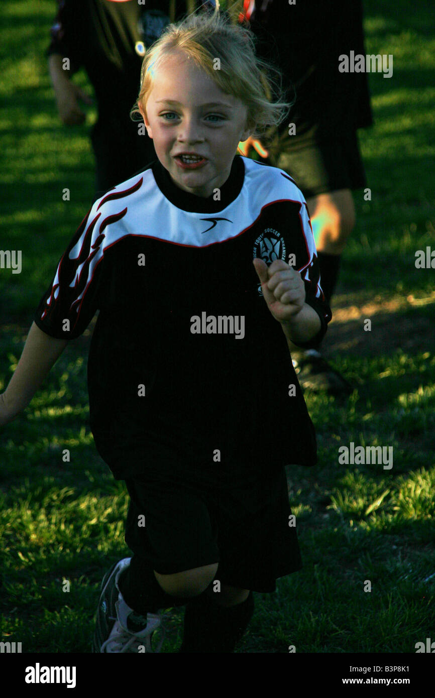 Cute blond child running in from soccer game Stock Photo - Alamy