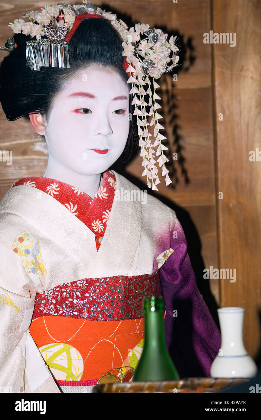 Japan, Kyoto. Maiko trainee geisha entertaining at dinner and serving ...