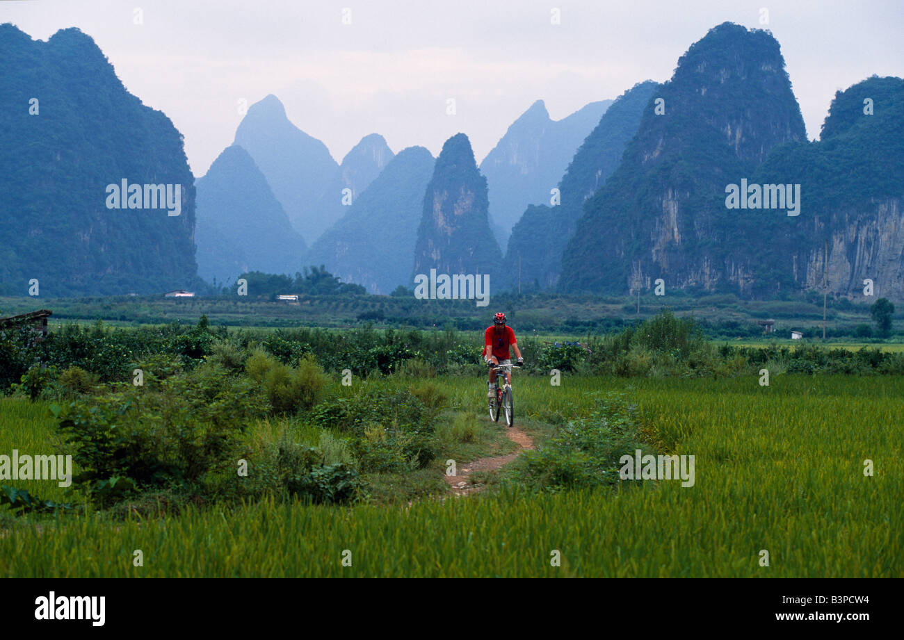 China, Guangxi Province, Guilin. Cycling beneath limestone pinnacles ...