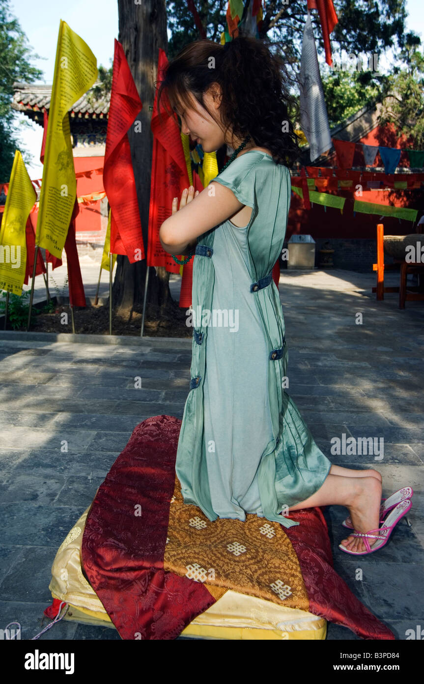 China, Beijing. Chinese girl (MR) praying at the Yuan Dynasty Miaoying ...